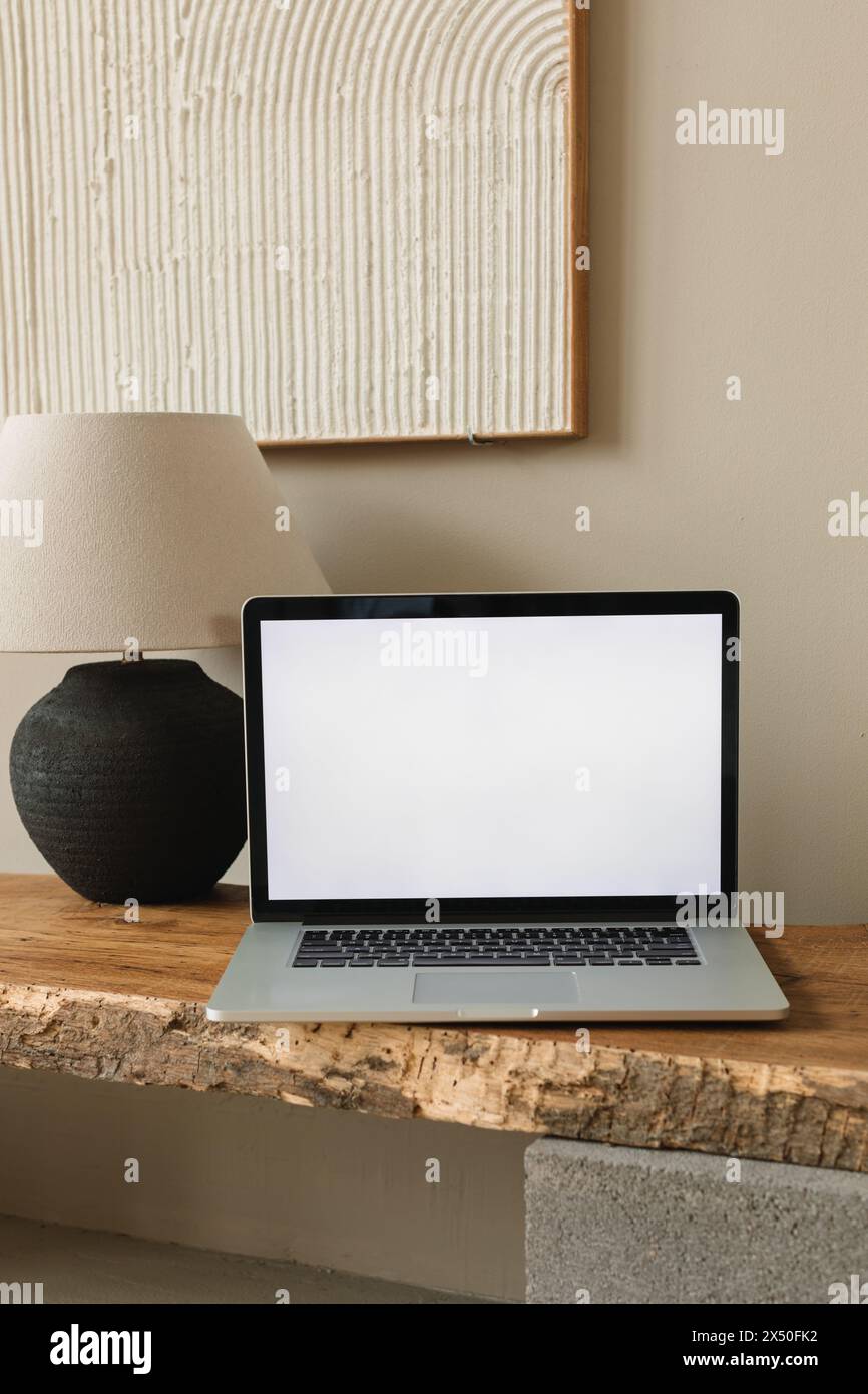 Open laptop computer with a blank screen on a table next to a lamp ...