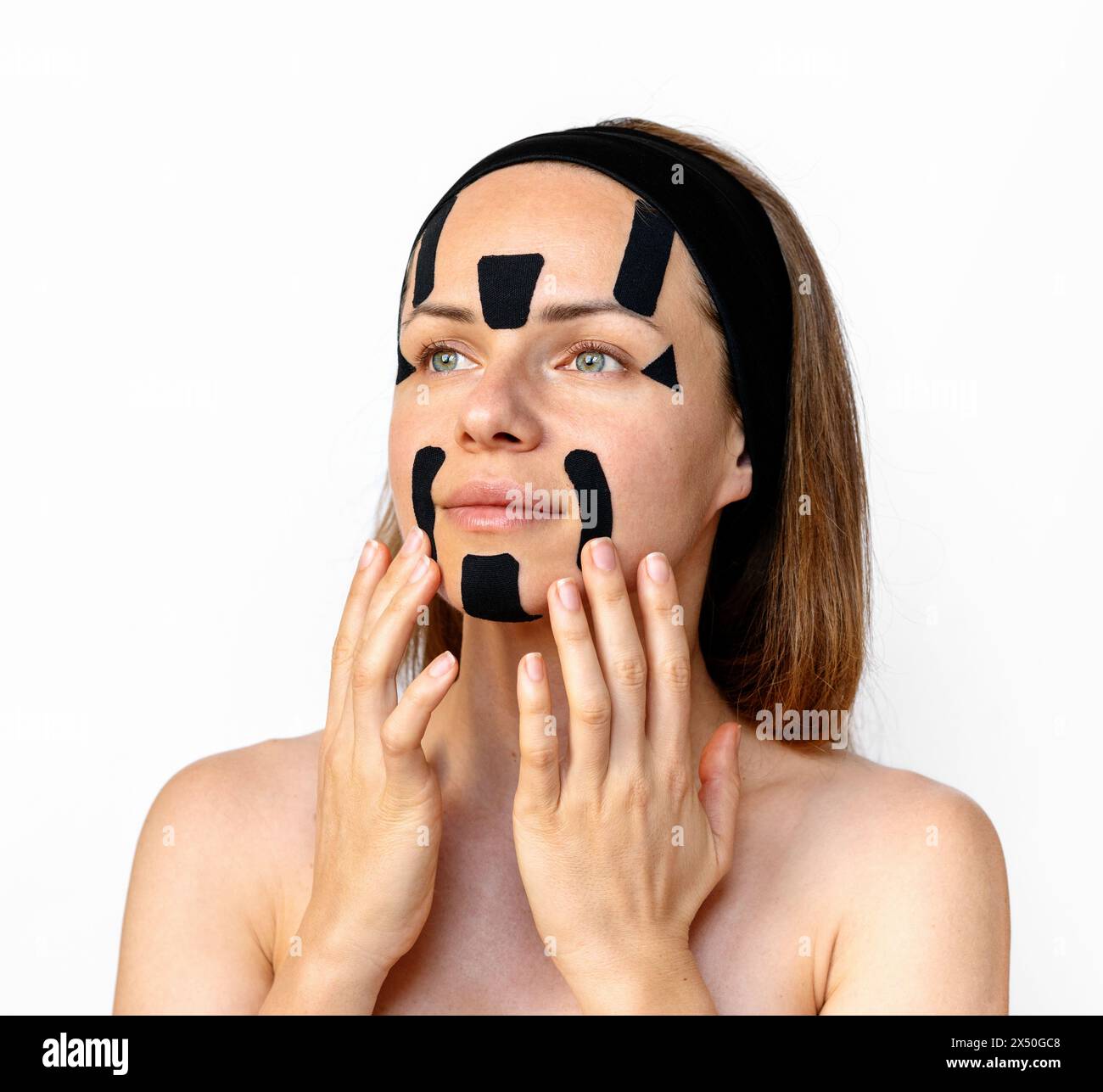Female beauty model applying kinesio facial tapes on her face against a ...