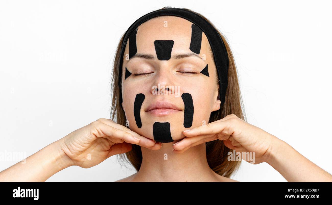 Woman beauty model applying black coloured kinesio facial tapes on her ...