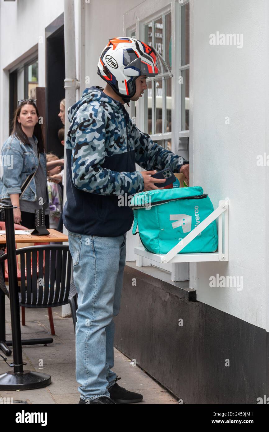 A deliveroo rider collecting a takeaway food order ready for delivery ...