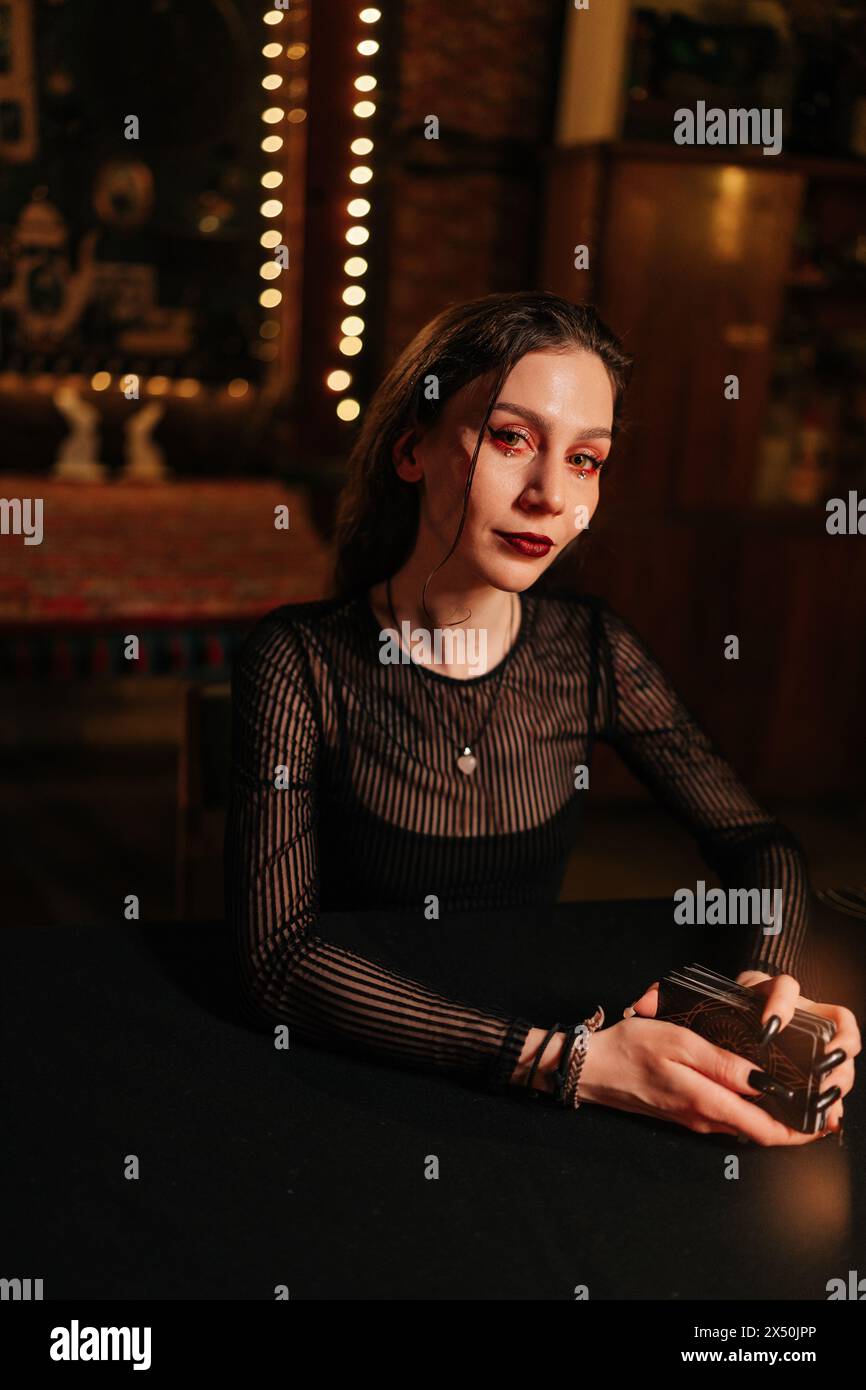 Vertical portrait of fortune teller female looking at camera, shuffles ...