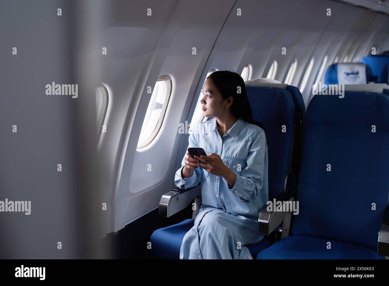Asian people female person onboard, airplane window, using mobile while ...
