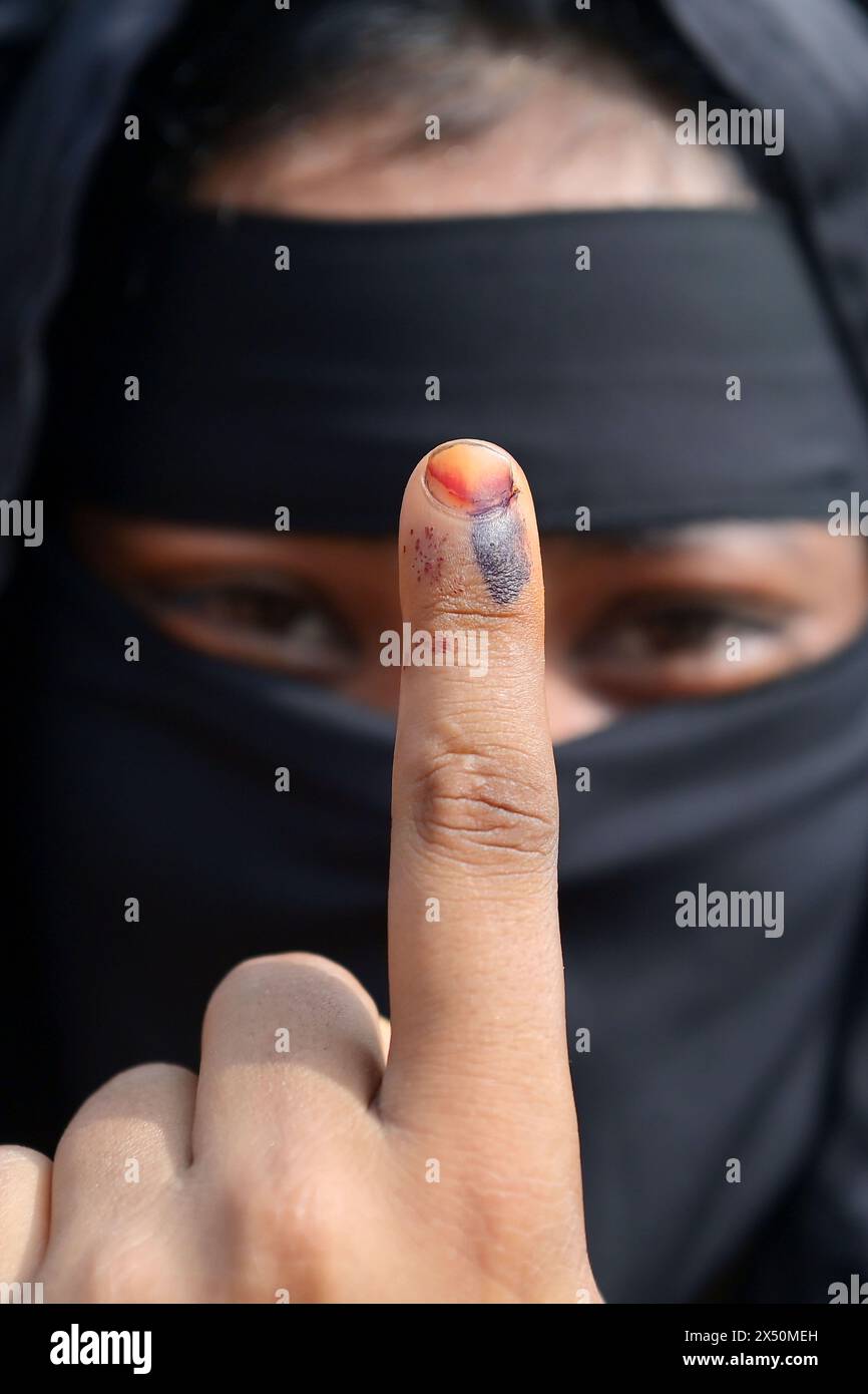 A muslim woman proudly displays her inked finger after voting in the ...