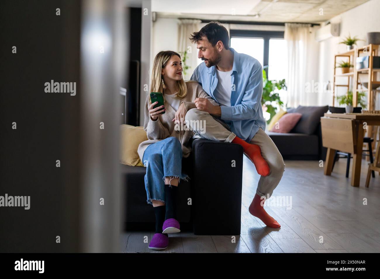 Happy young couple, woman and man hugging, using smartphone together ...