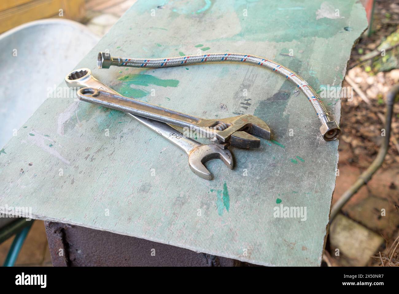 Tools rest haphazardly on a weathered workshop table, touched by the ...