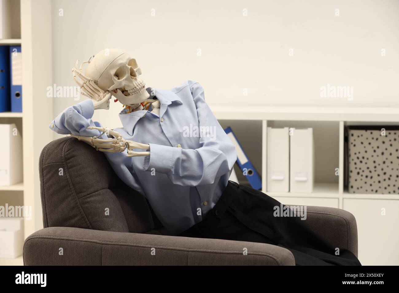Waiting concept. Human skeleton sitting in armchair at office Stock ...