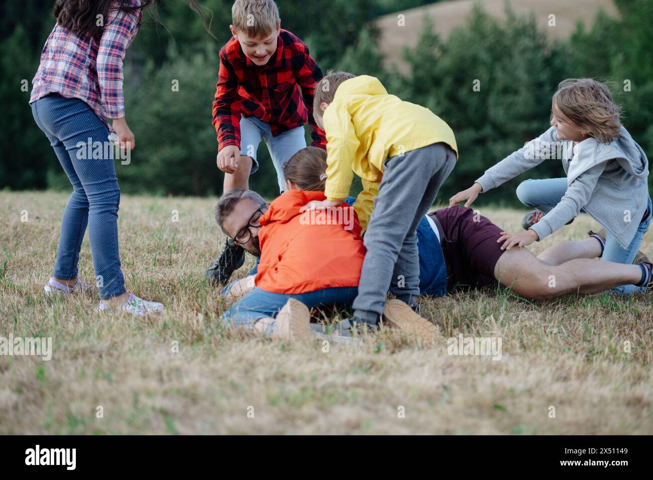 Young students playing with teacher outdoors, in nature, during field ...