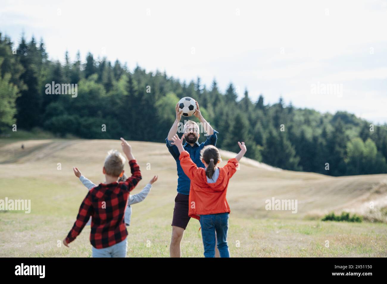 Young students playing with teacher outdoors, in nature, during field ...