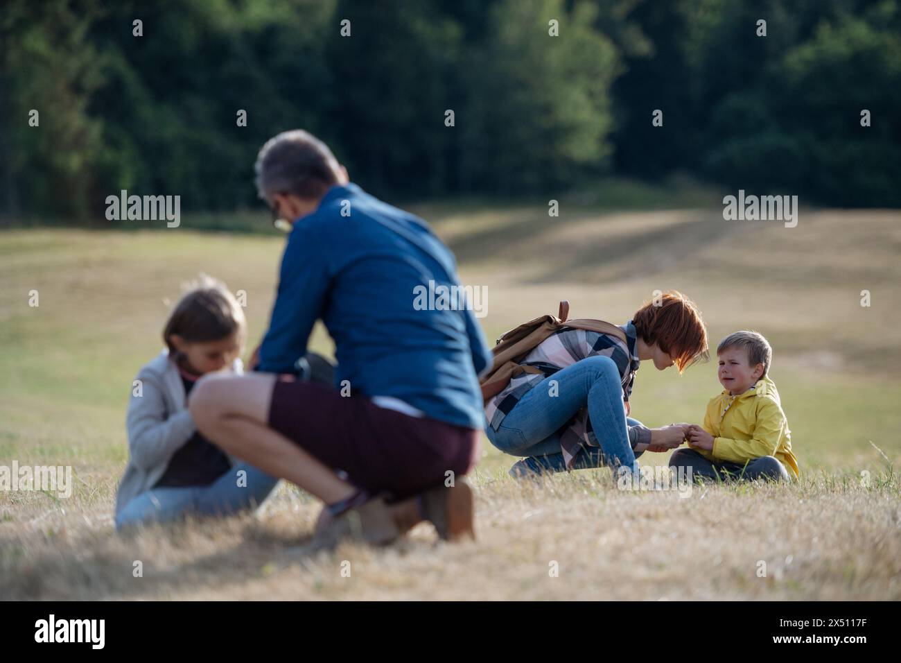 Teacher helping injured boy after fall. Young students running across ...