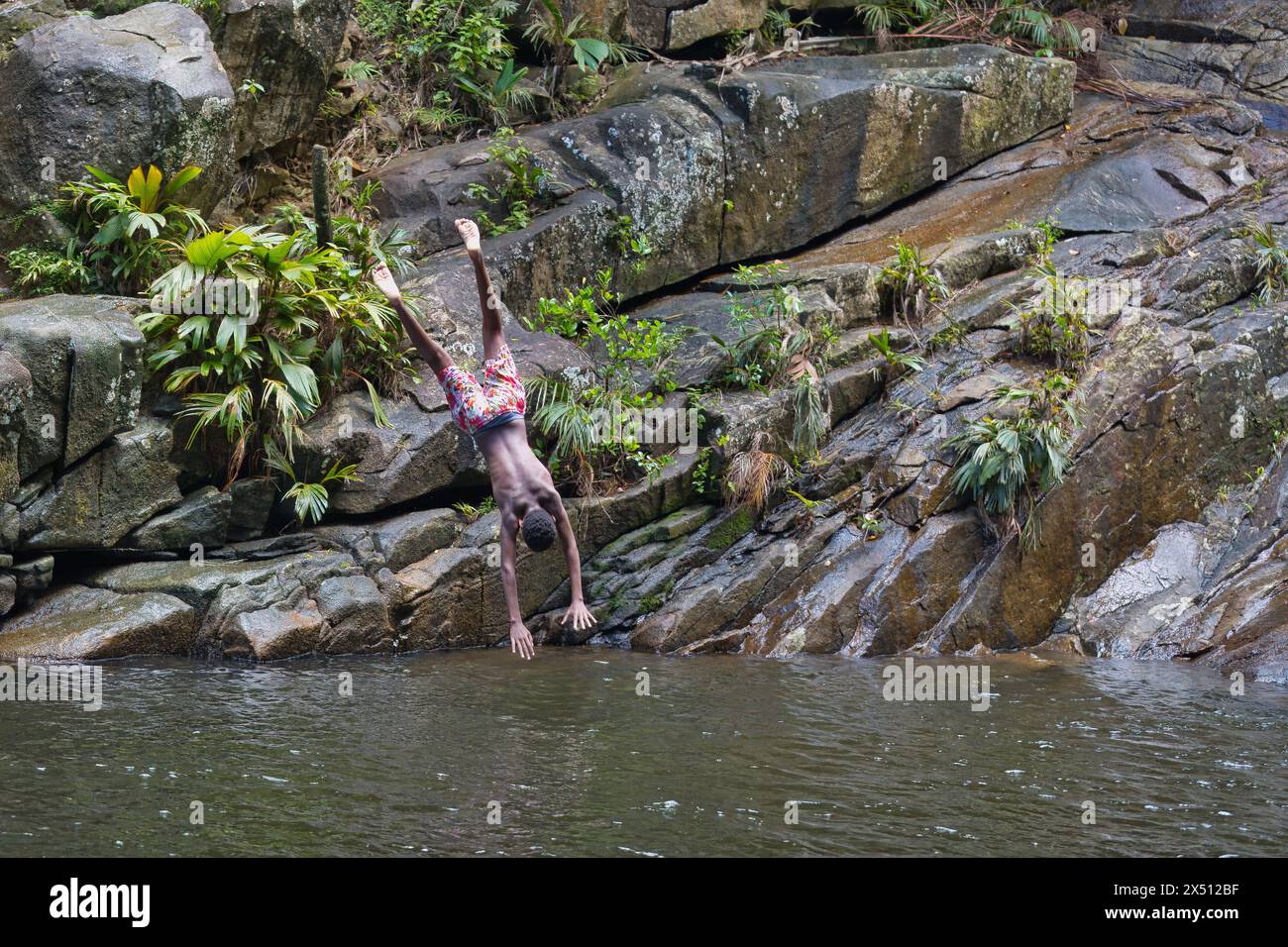 Mahe, Seychelles 6.05.2024 Young boys having fun diving from granite ...