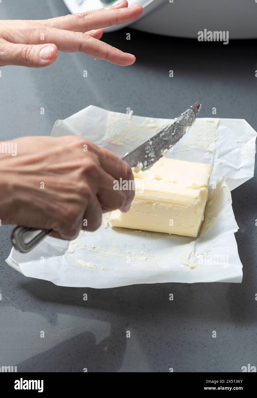 slicing butter on parchment, with scattered crumbs on a sleek gray ...