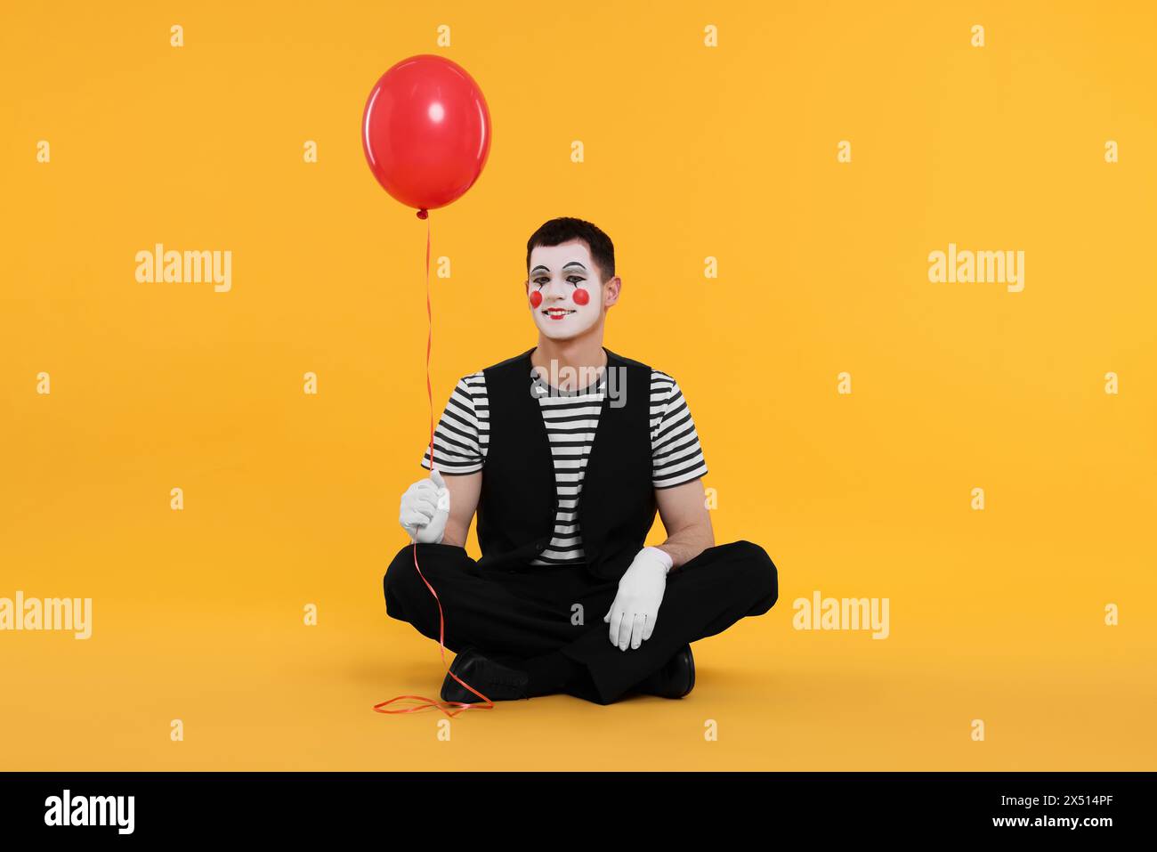 Funny mime artist with balloon on orange background Stock Photo - Alamy