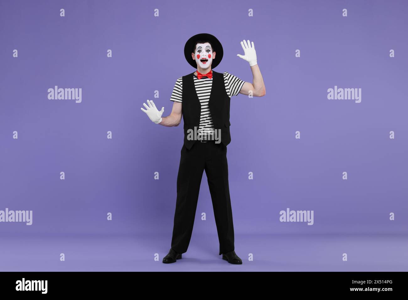 Mime artist making excited face on purple background Stock Photo - Alamy