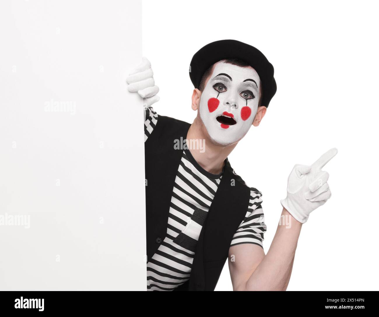 Funny mime artist peeking out of blank poster and pointing at something ...