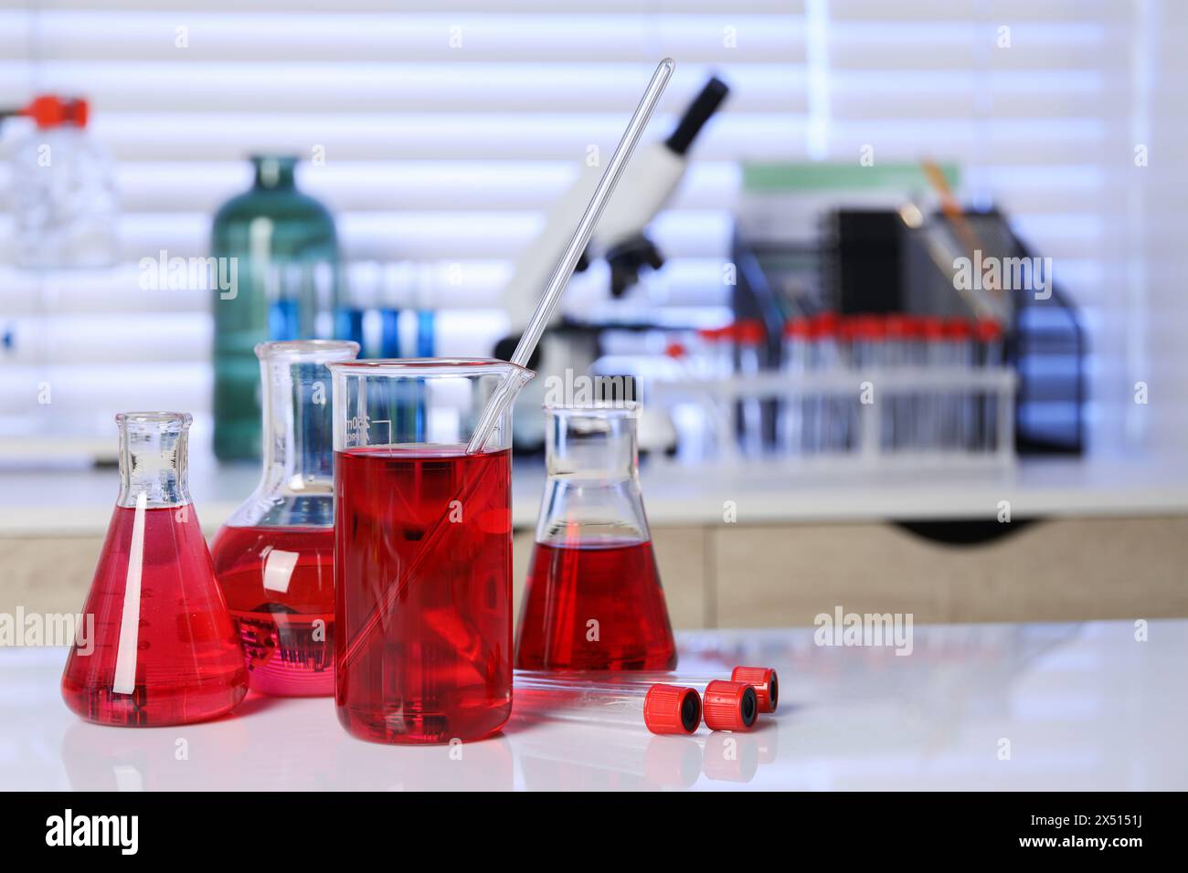 Laboratory analysis. Different glassware with red liquid on white table ...