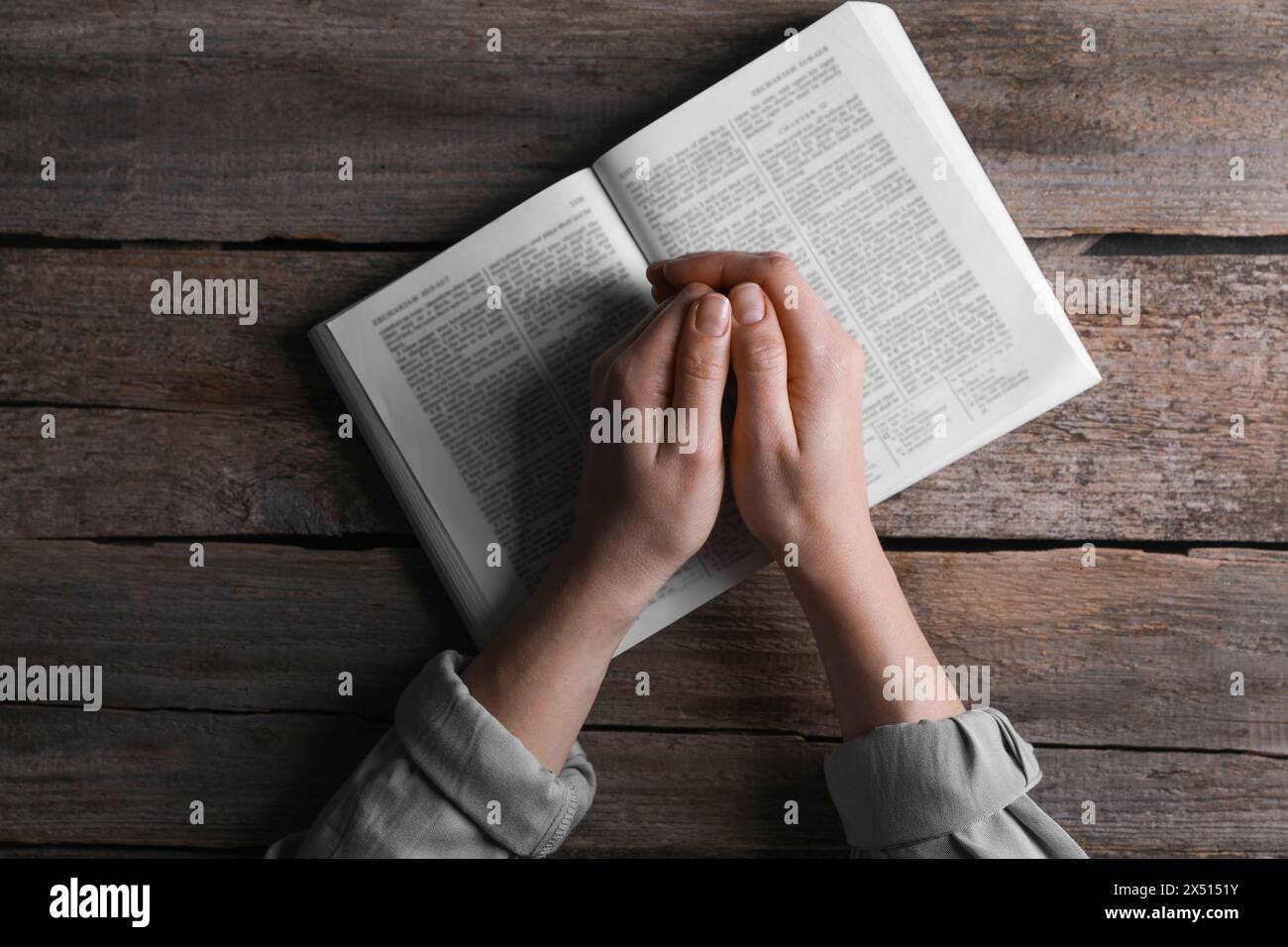 Religion. Christian woman praying over Bible at wooden table, top view ...