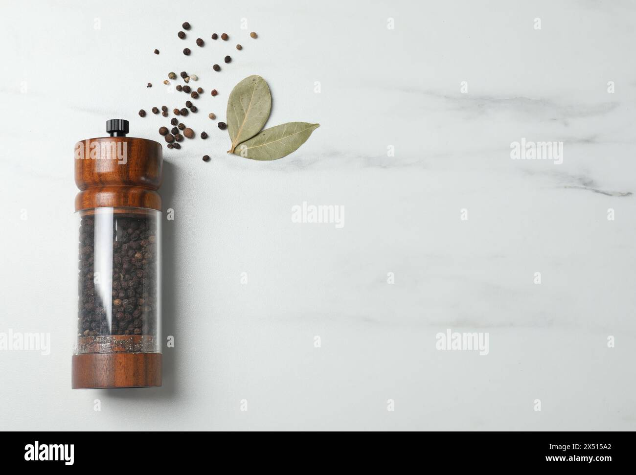 Pepper shaker and bay leaves on white marble table, flat lay. Space for ...