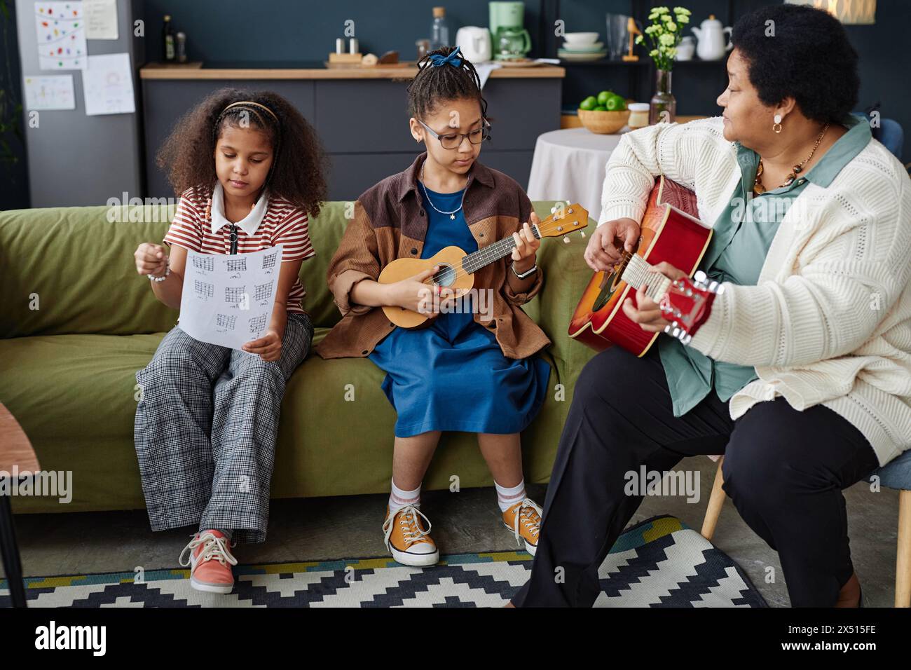 Portrait of Black senior woman with two girls playing musical ...