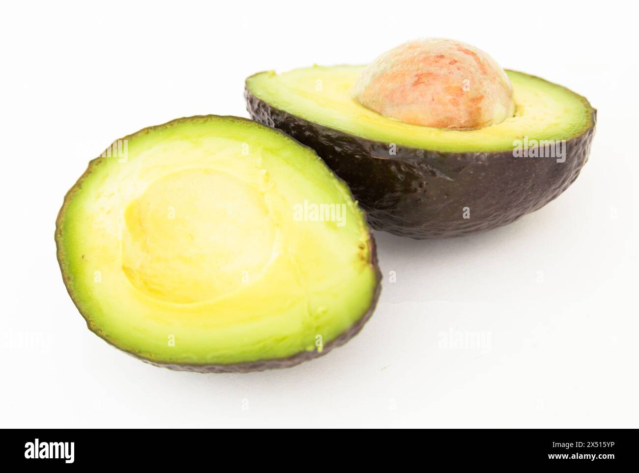 Halved avocado with bone on white background Stock Photo - Alamy