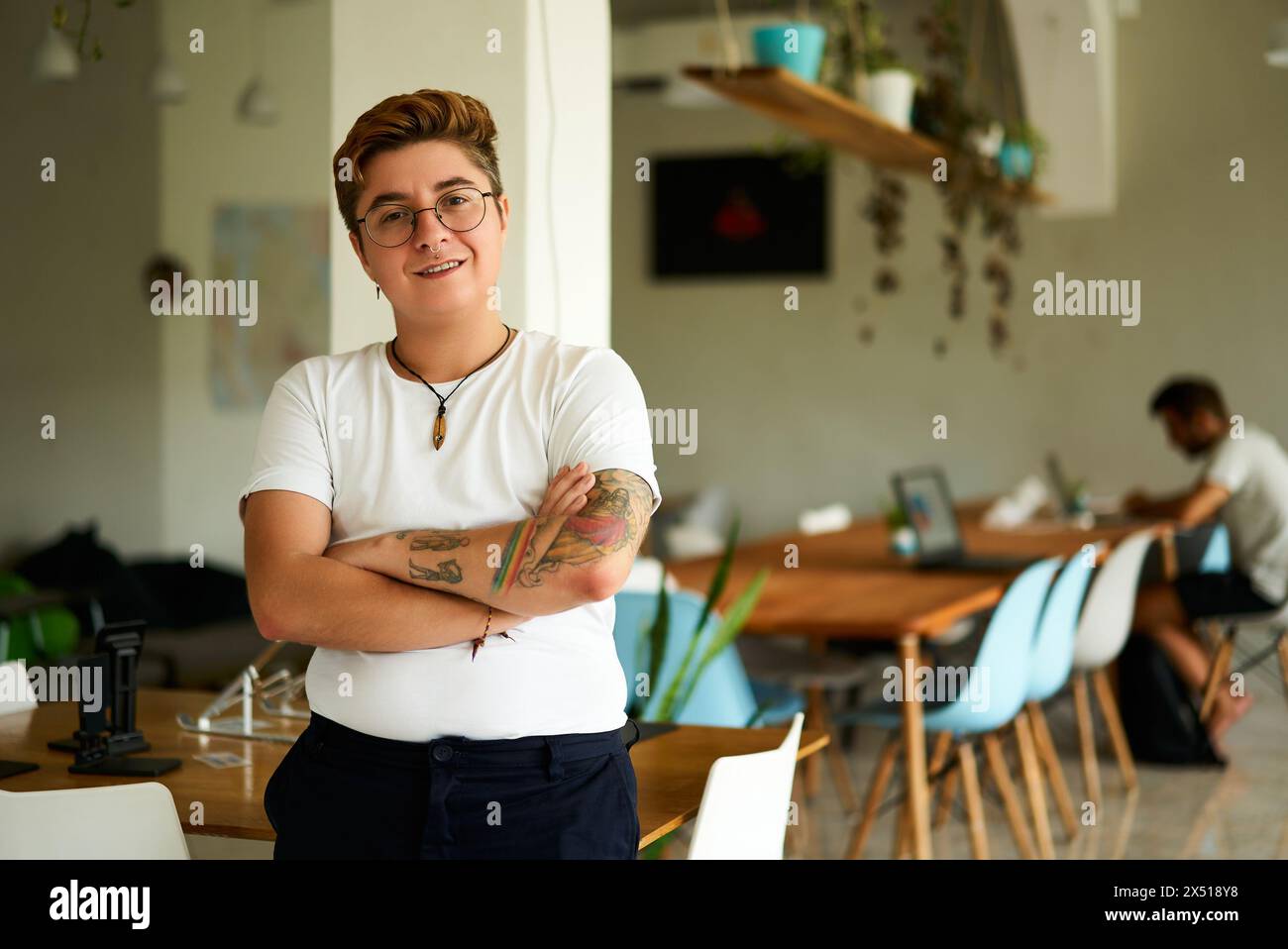 Confident transgender pro in casual office attire stands with arms ...