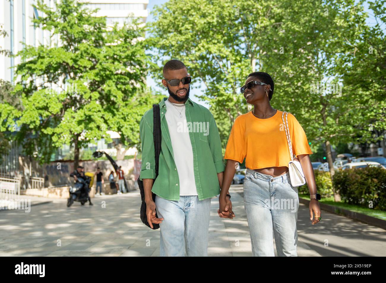 Happy contented loving couple walks holding hands in city chatting ...