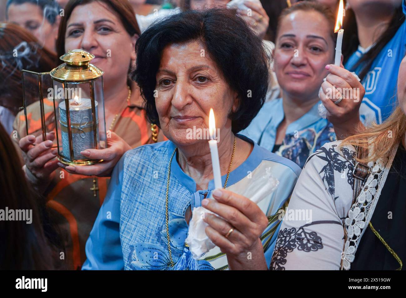 Syriac Orthodox Christian woman holds lit candles during the ceremony ...