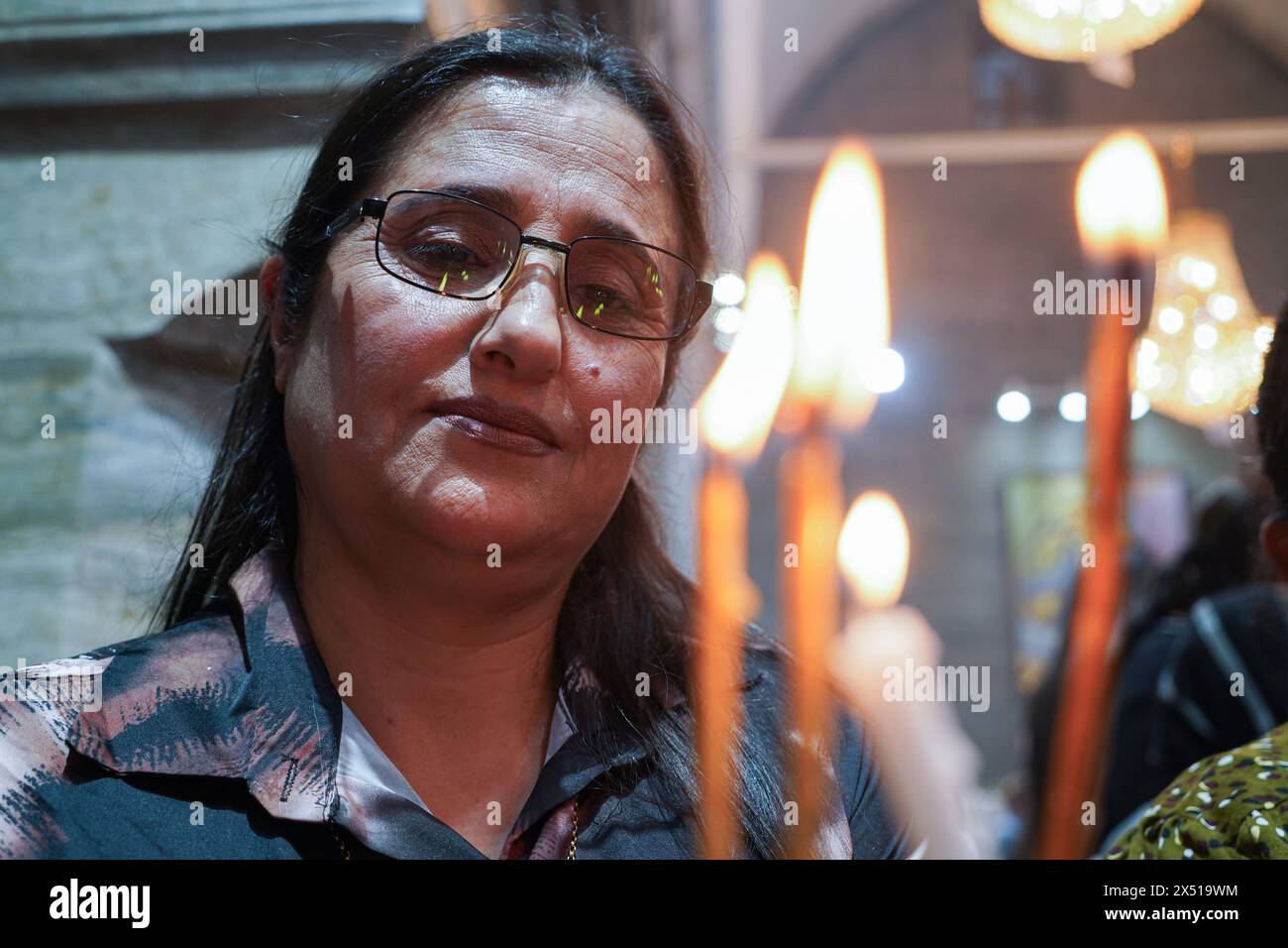 Syriac Orthodox Christian woman holds lit candles during the ceremony ...