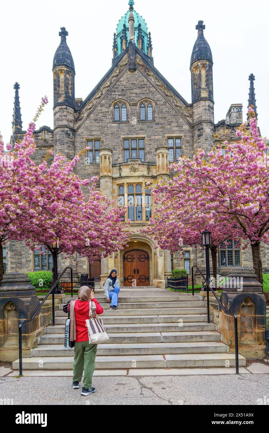 People taking pictures by cherry trees with flowers and colonial ...