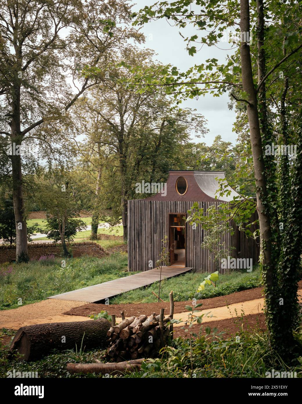 The apiary pavilion seen between the trees with a path winding towards ...
