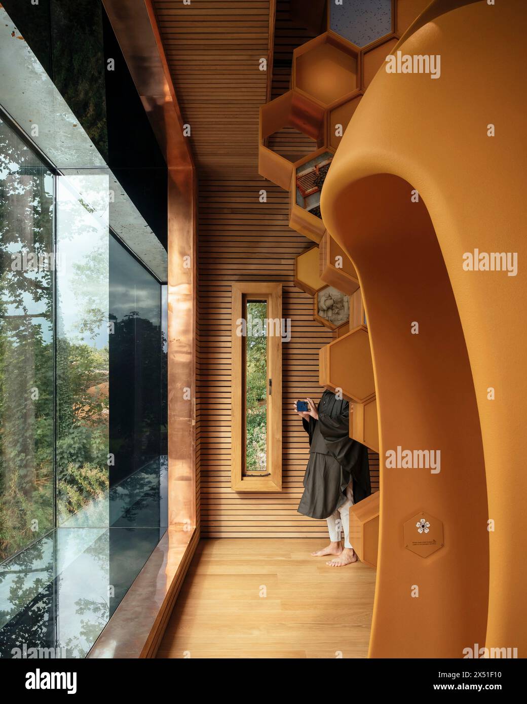 A visitor snaps a picture through a large window. Seating pod in the ...