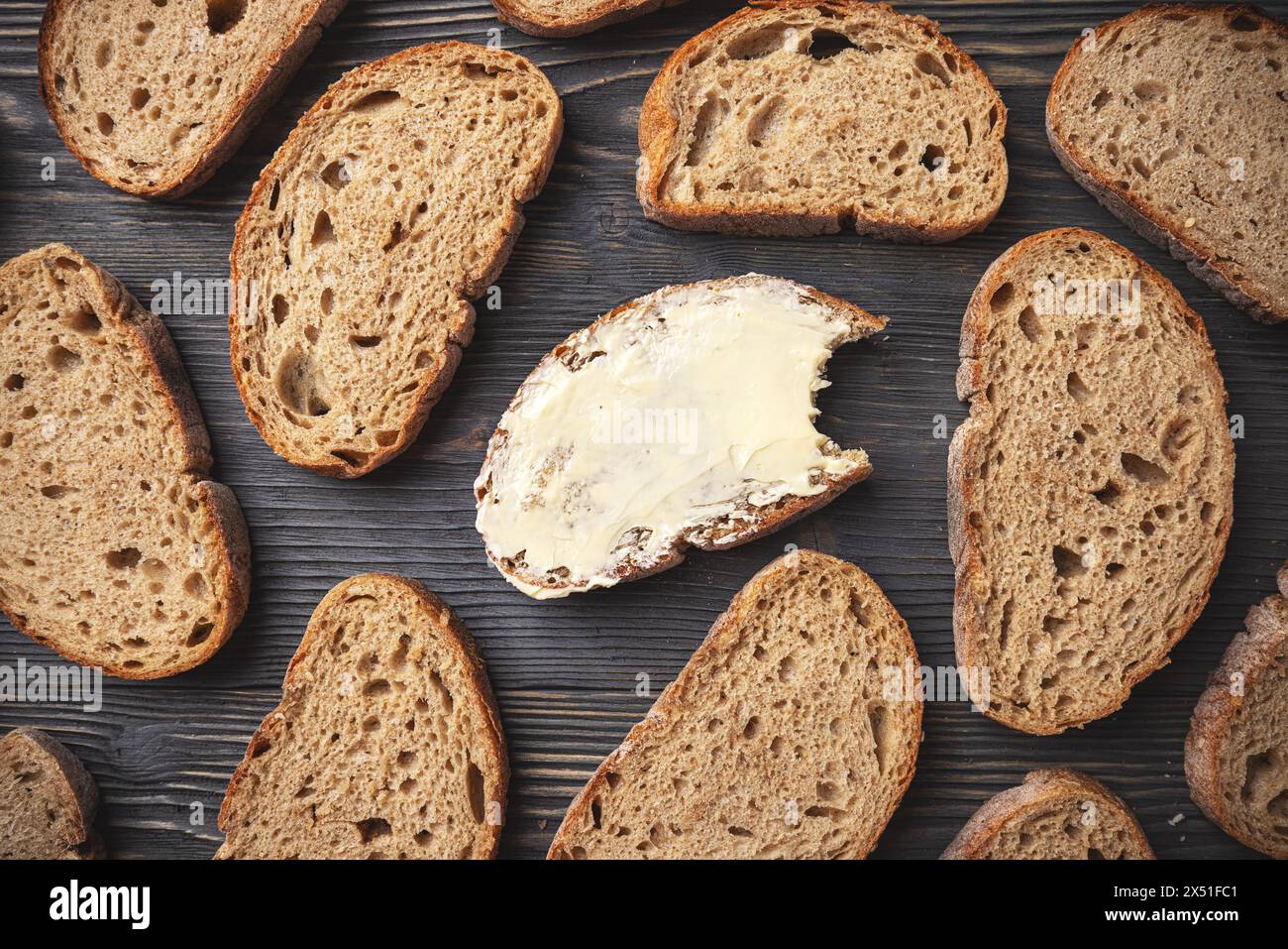 Top view of sliced whole grain bread with a buttered piece, on a rustic ...
