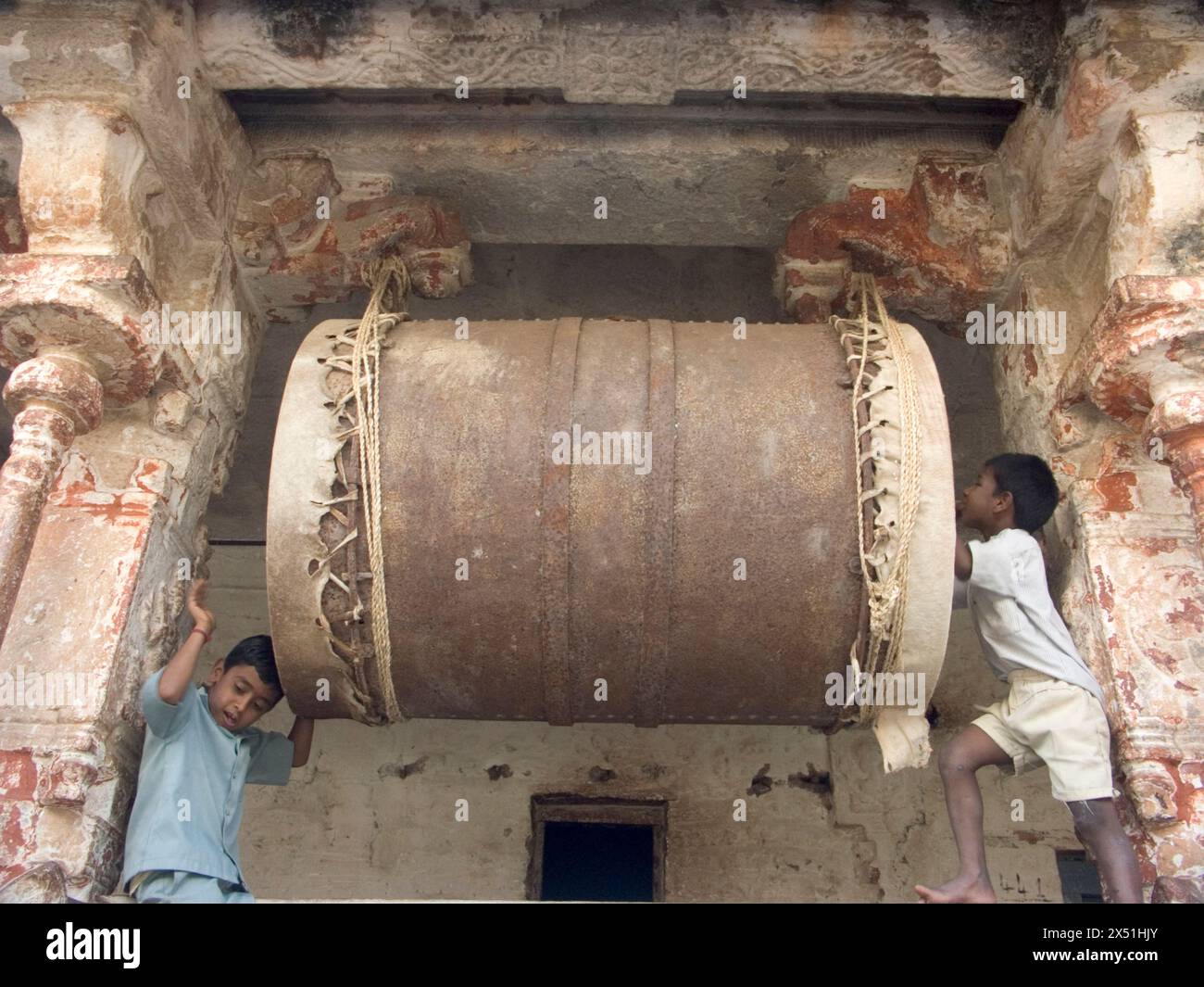 Kids bang on a vast drumin the Hindu temple in Hampi, Karnataka, India ...