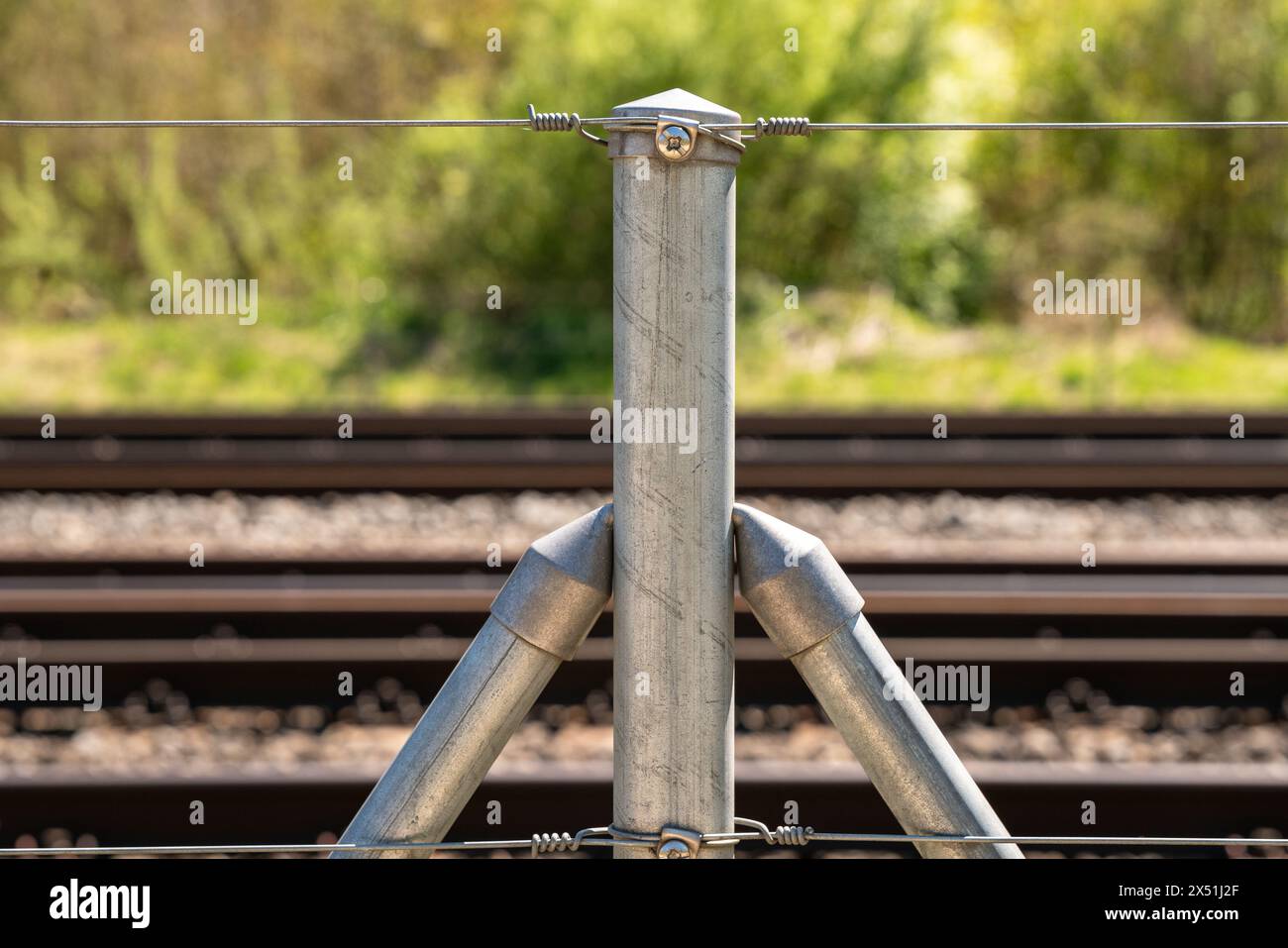 Close up of fencing of railroad tracks. Bushes and trees in the ...