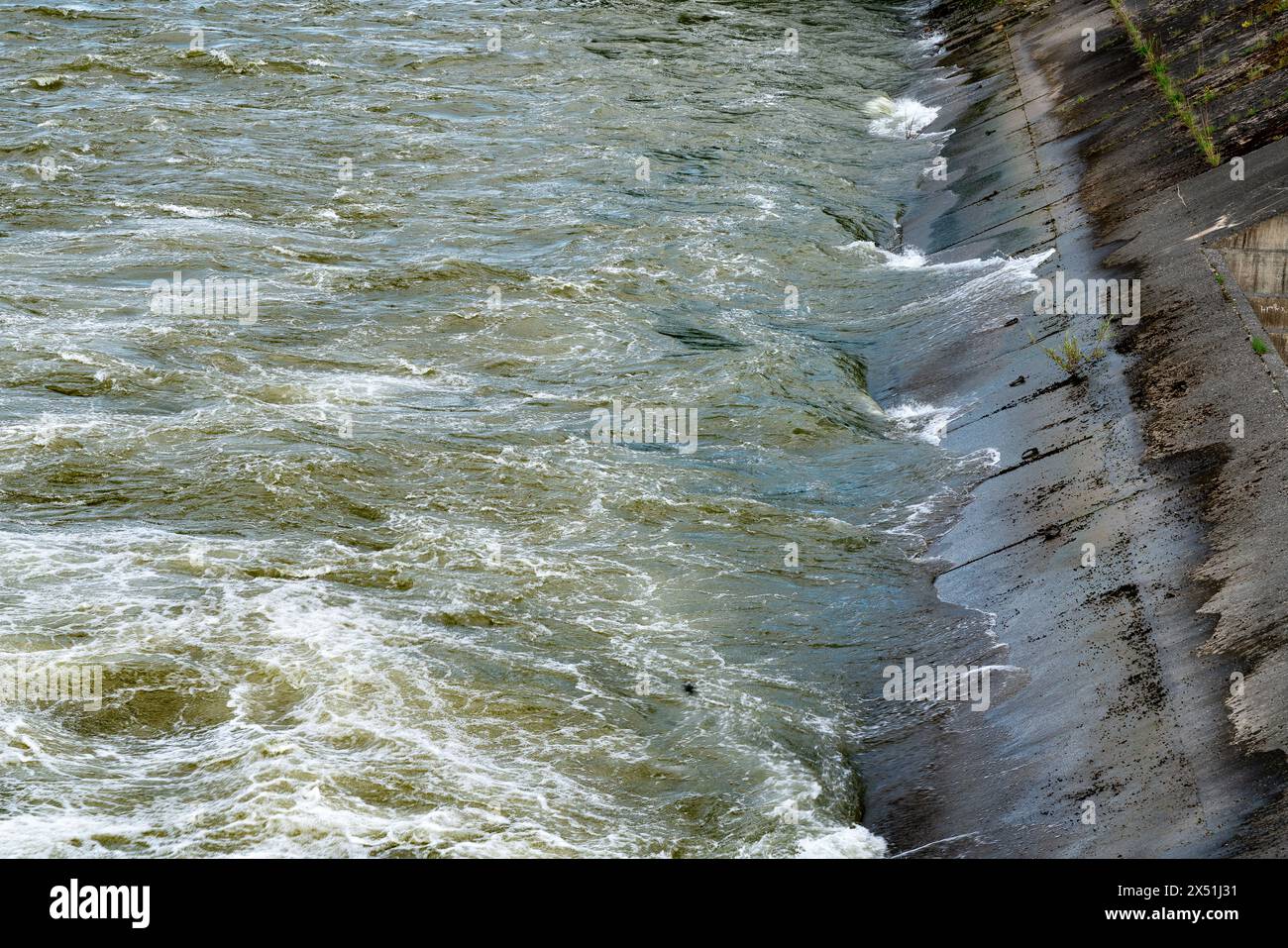 Texture of water with spray rolling against a river bank with weathered ...