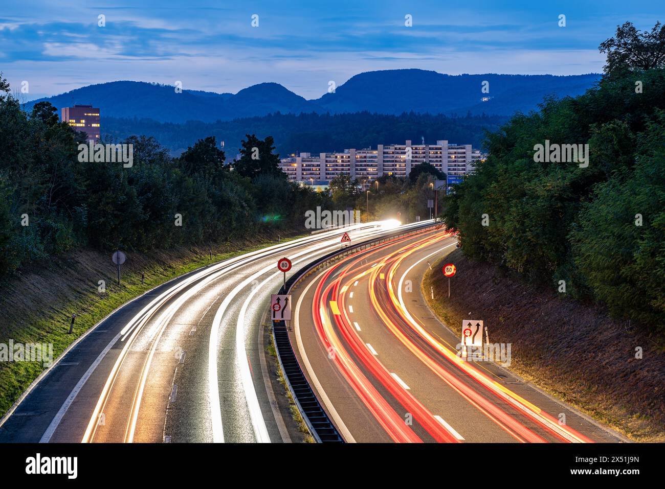 Traffic on a road painting light trails. Road signs warn of a ...