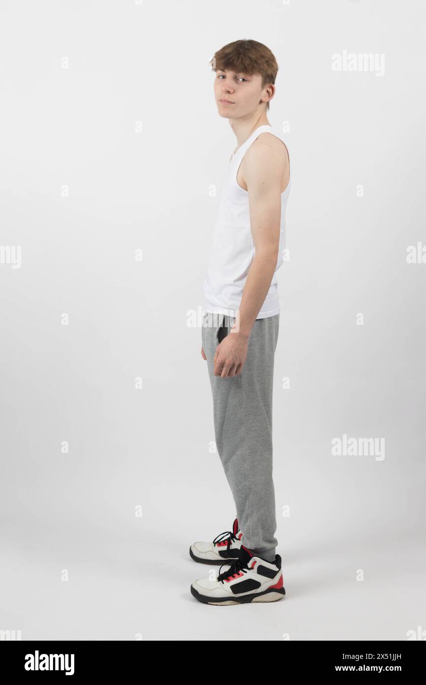 A Fifteen Year Old Teenage Boy Standing Against A White Background Standing To The Side. Facing ...
