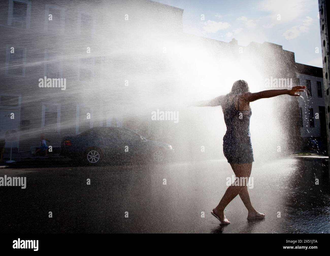 A woman cools off in an open fire hydrant Stock Photo - Alamy