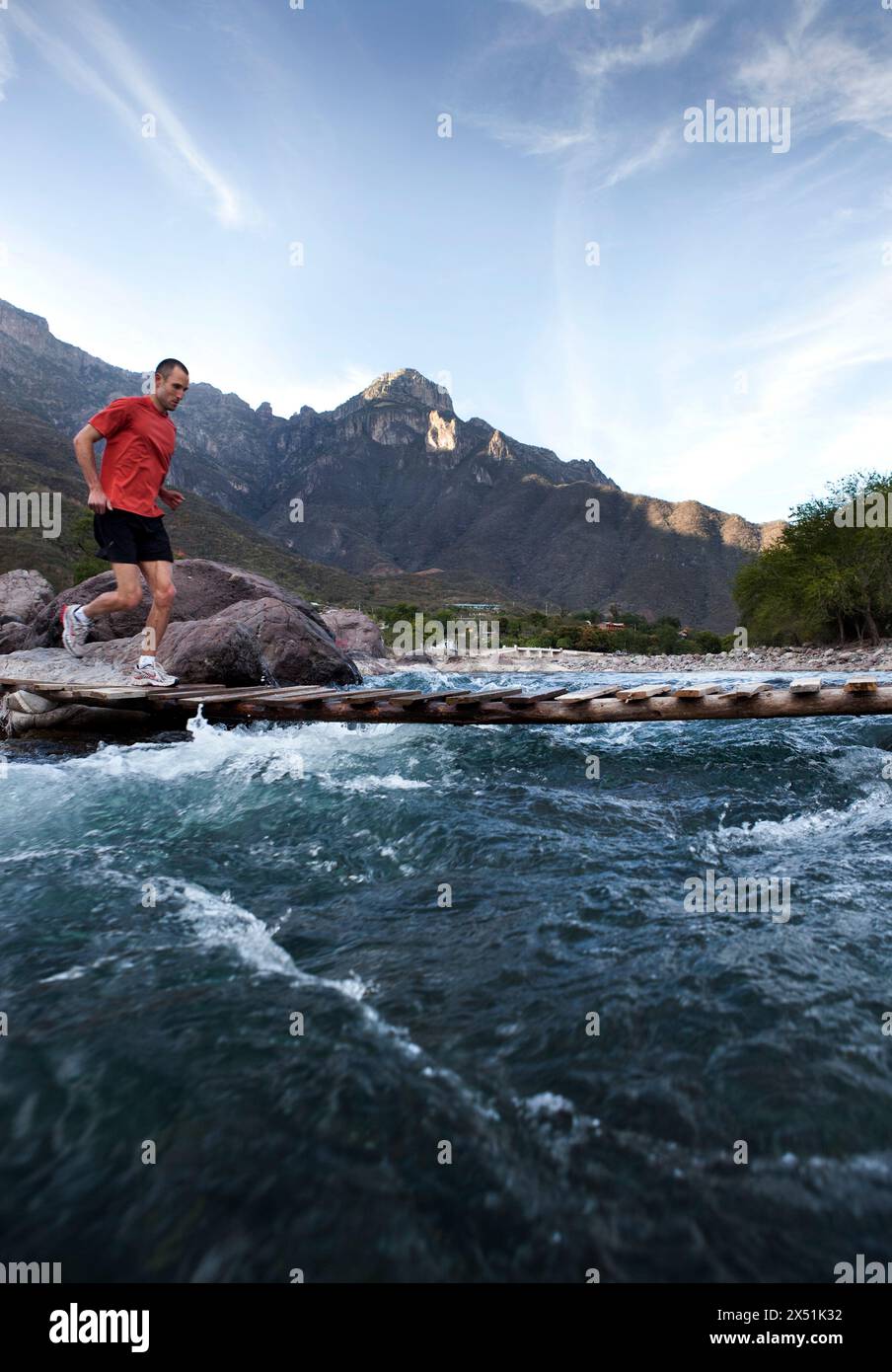 A runner crosses a river using a wooden bridge Stock Photo - Alamy