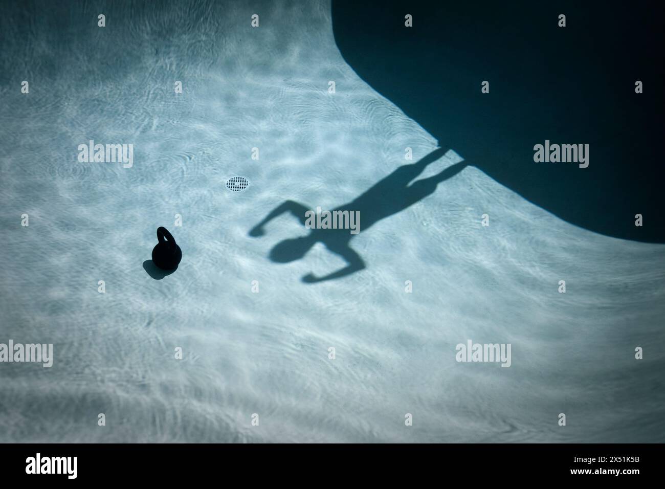 A man flexing casts a shadow on the bottom of a pool where a kettle ...