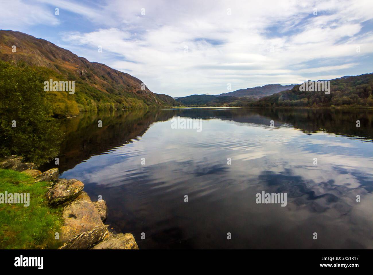 An almost perfect reflection of the blue sky and feathery clouds in the ...