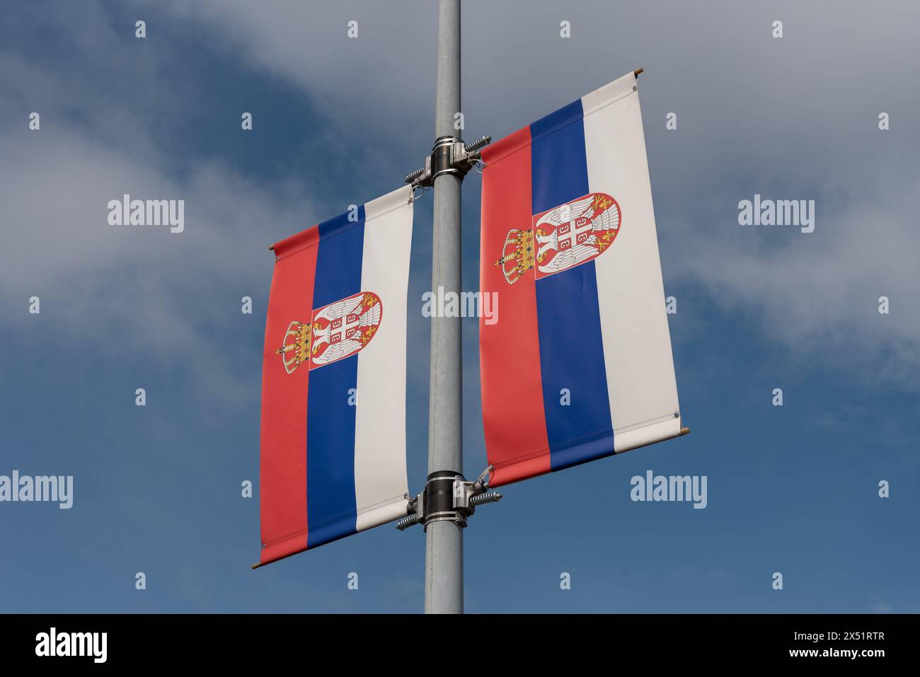 Pair of Serbian flags outdoors on a pole with a cloudy sky behind Stock ...