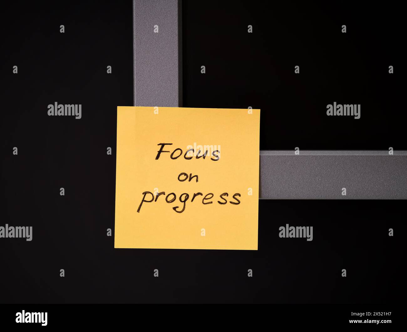 Yellow paper note with the reminder Focus on Progress on it sticked on ...