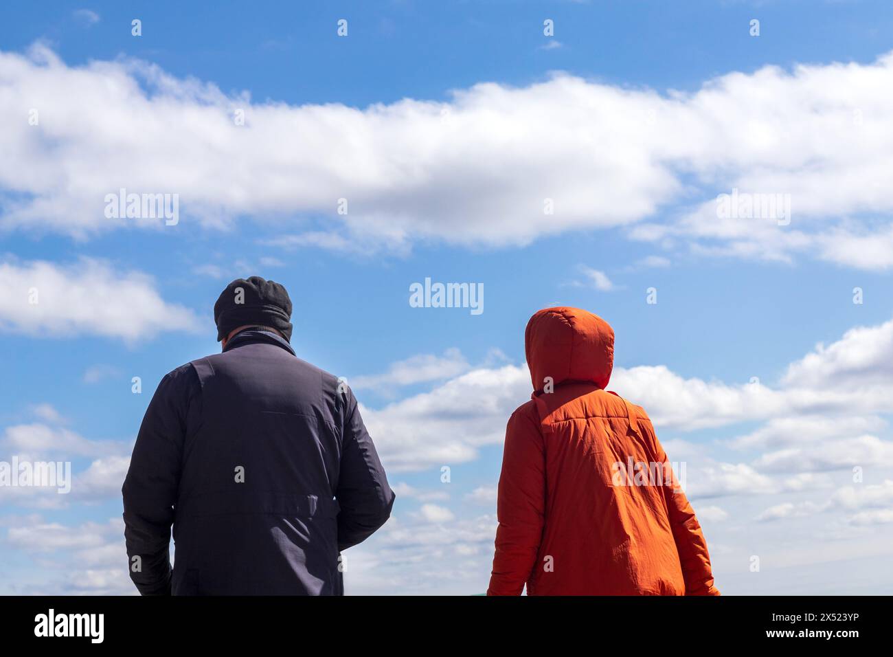 person in red color and black color coat on the background of blue sky ...