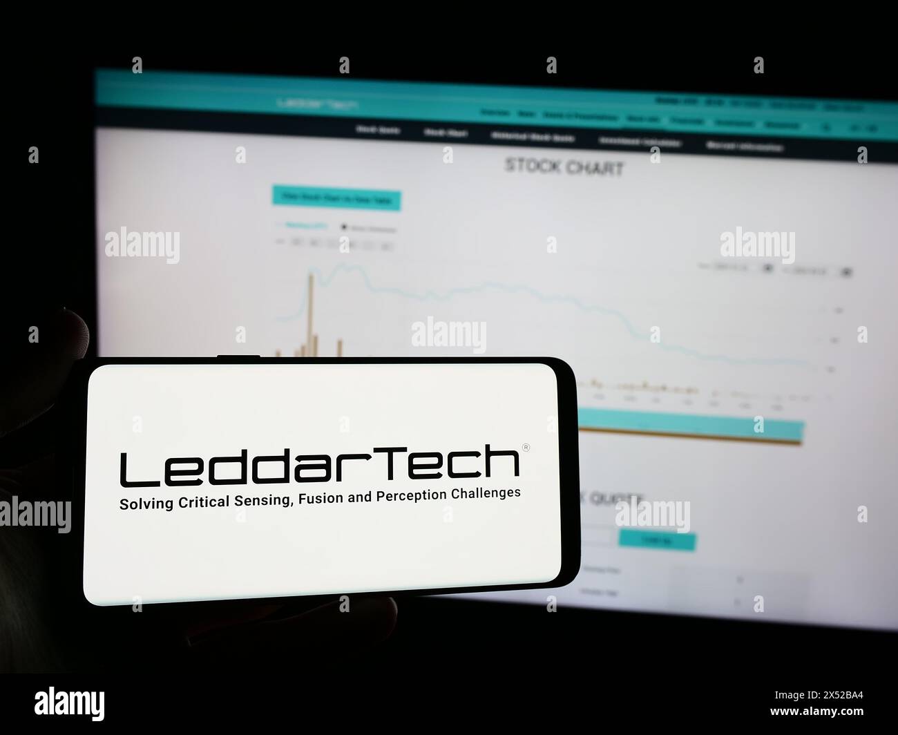 Person holding mobile phone with logo of Canadian lidar company ...