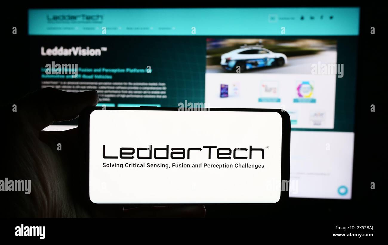 Person holding cellphone with logo of Canadian lidar company LeddarTech Holdings Inc. in front ...