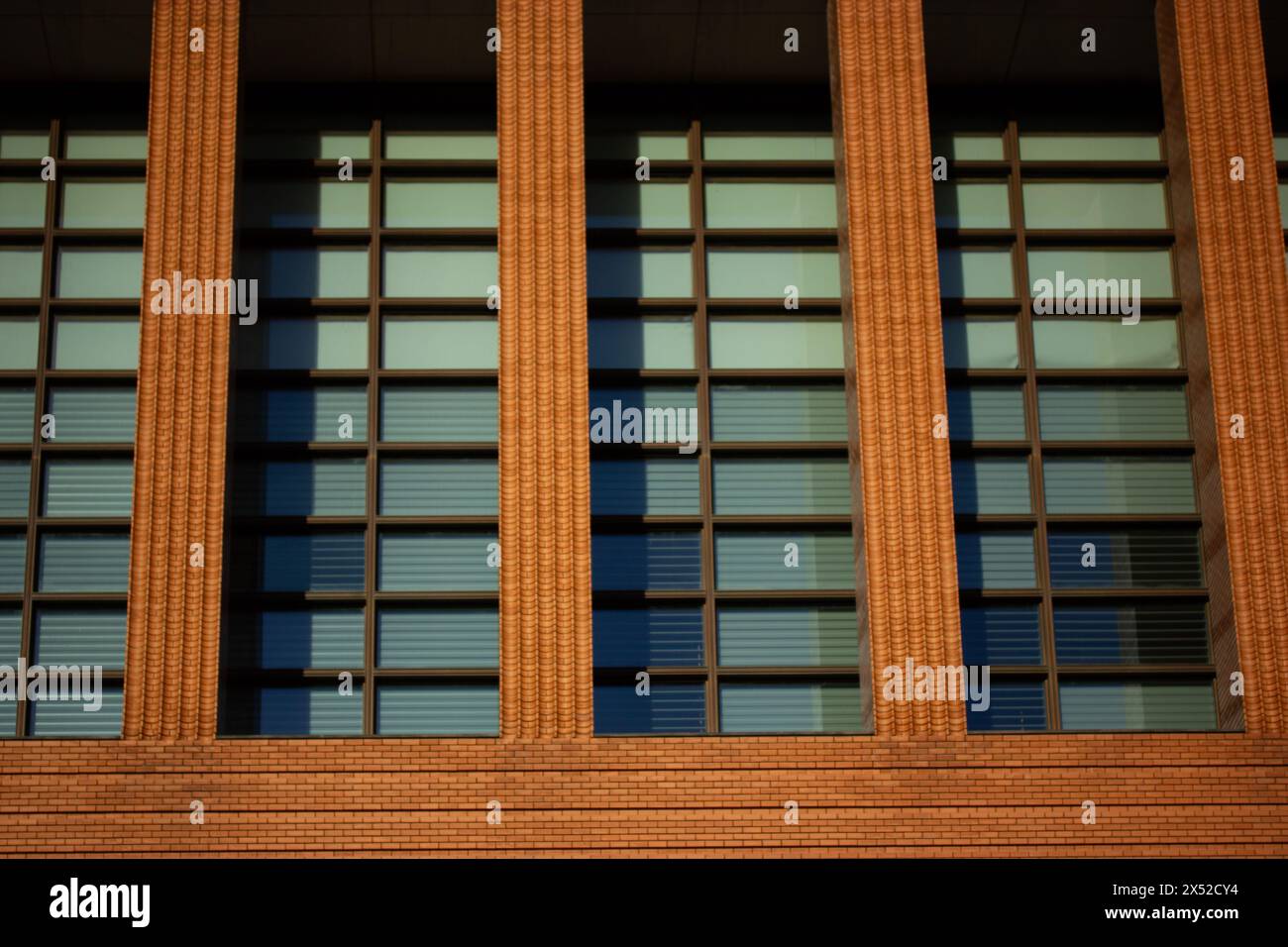 Close up detail of modern orange brick building facade with blue tinted ...