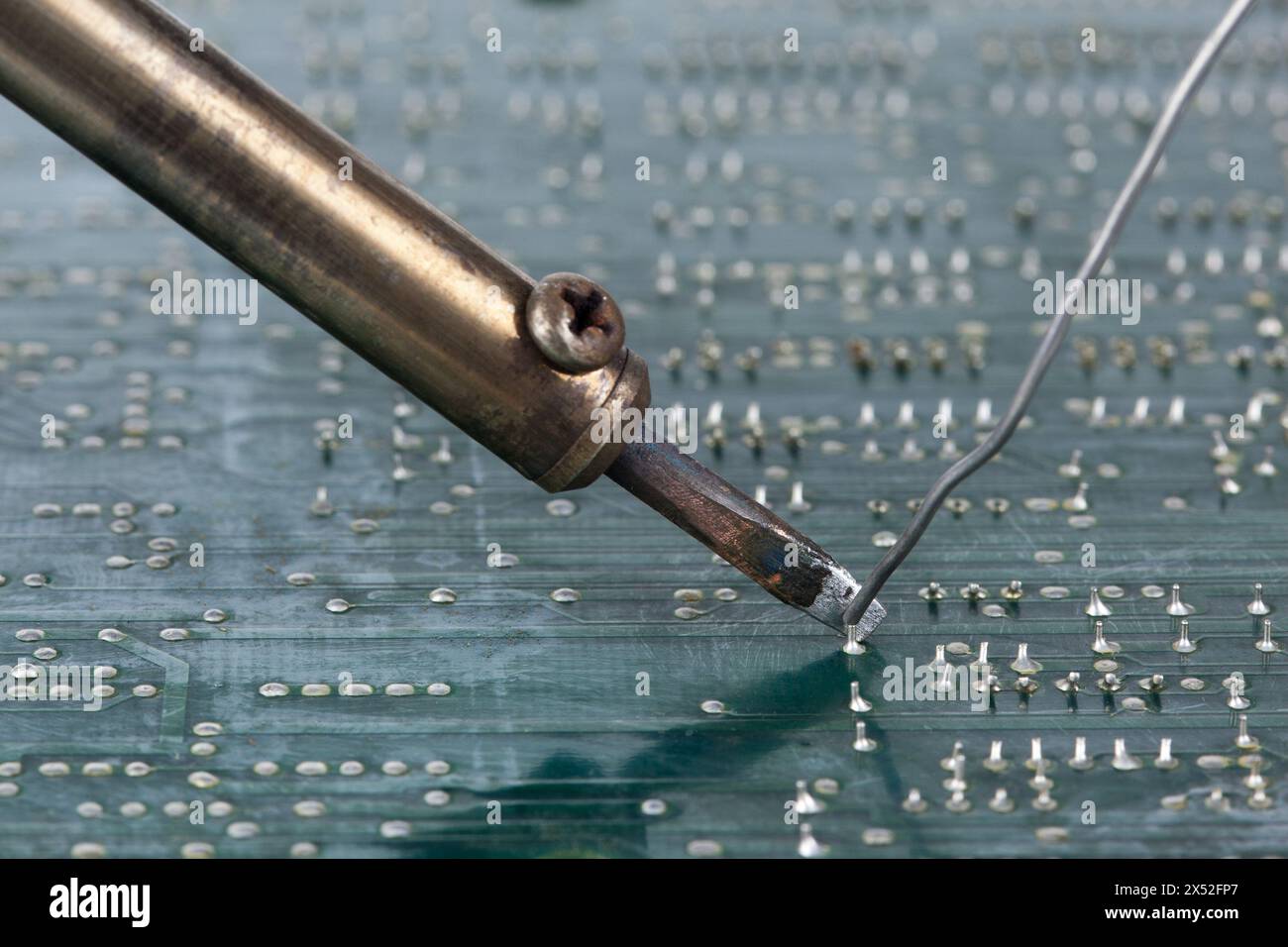 A soldering iron is carefully placed on the back of the circuit board ...
