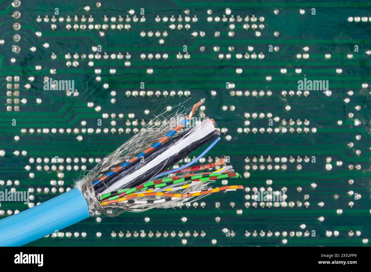 An stripped cable reveals several colored wires against a circuit board ...