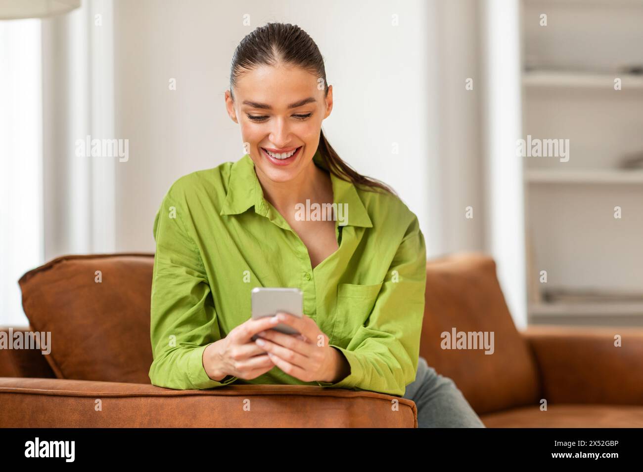 Woman Sitting on Couch Using Cell Phone at Home Stock Photo - Alamy