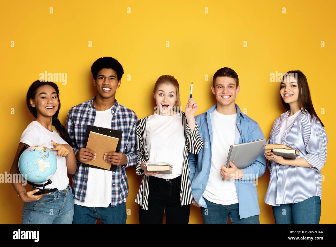 Group of Diverse Students Holding Educational Materials Against Yellow ...
